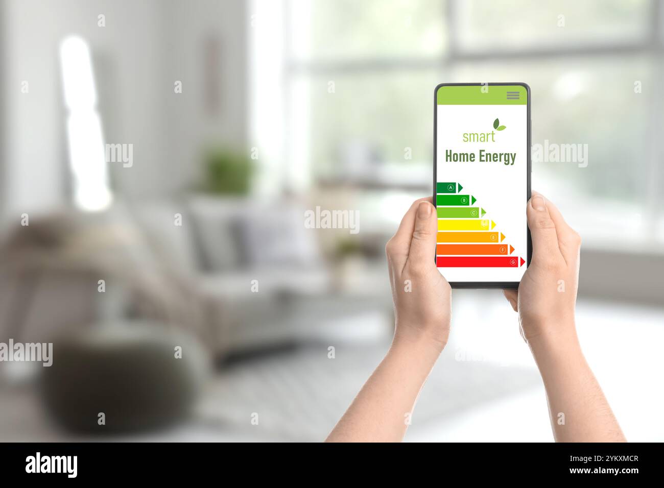Hands holding mobile phone with energy efficiency rating on screen in ...