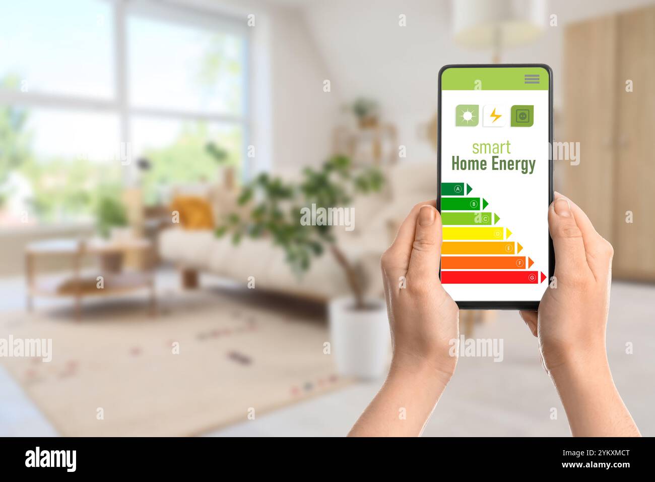 Hands holding mobile phone with energy efficiency rating on screen in ...