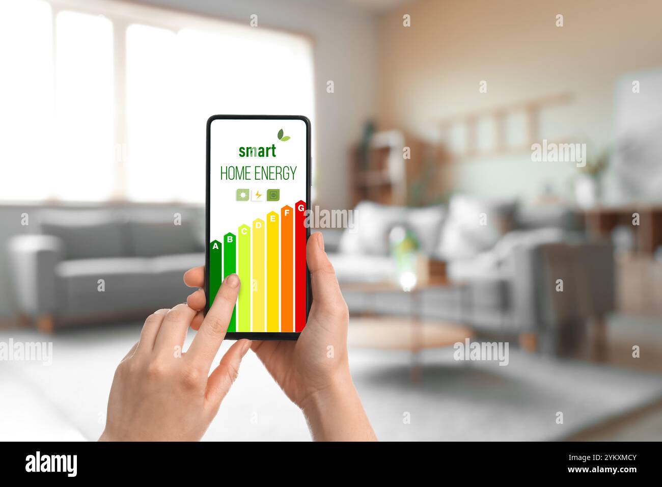 Hands holding mobile phone with energy efficiency rating on screen in ...