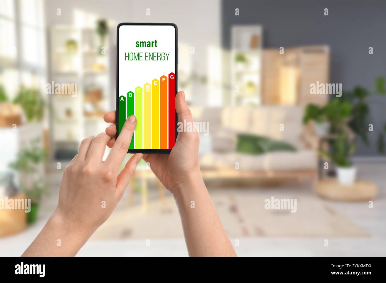 Hands holding mobile phone with energy efficiency rating on screen in ...