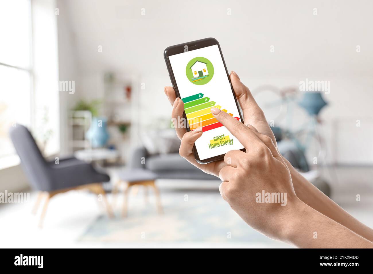 Hands holding mobile phone with energy efficiency rating on screen in ...