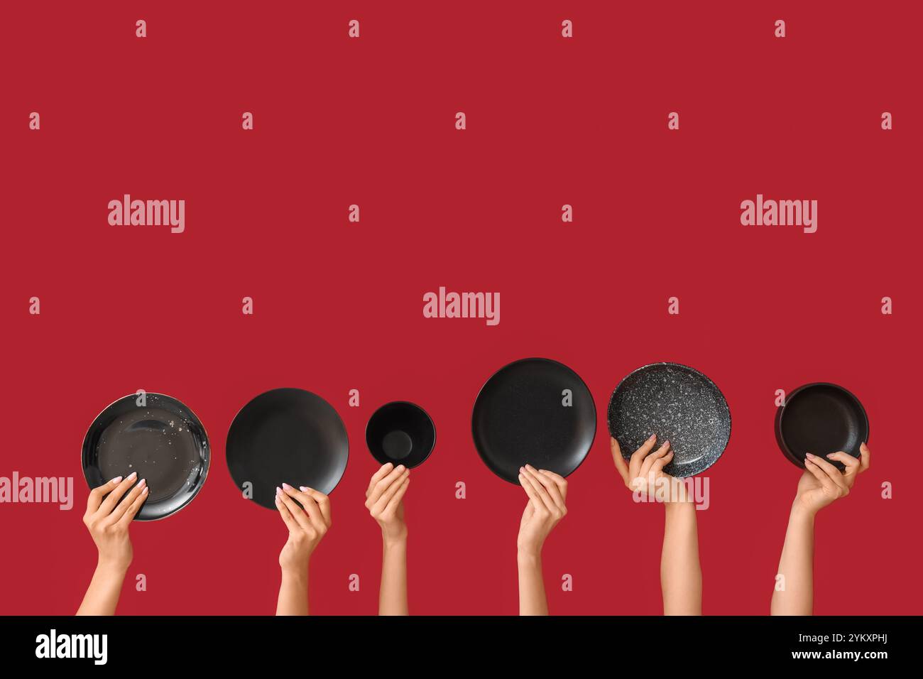 Hands holding empty plates on red background Stock Photo - Alamy