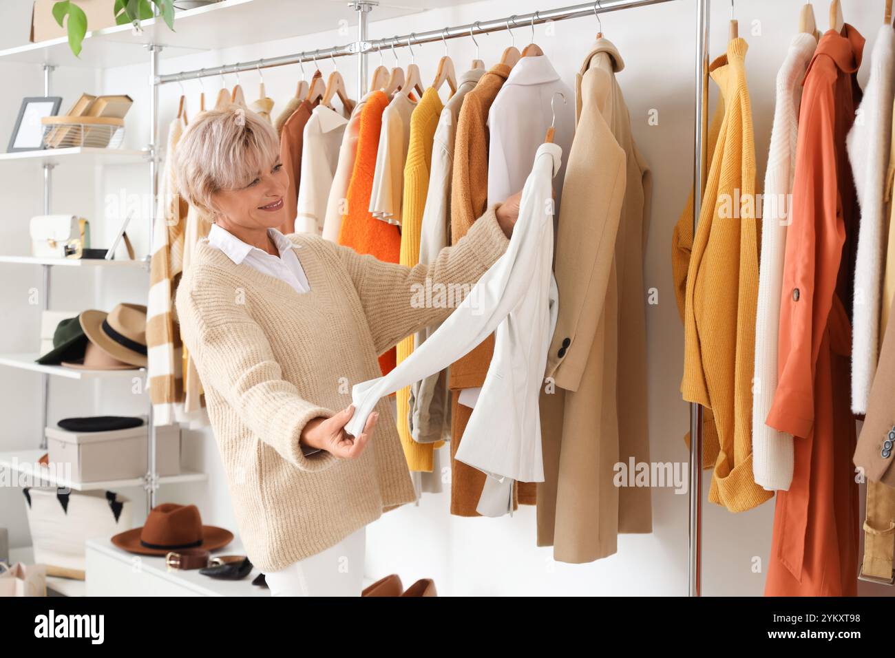 Happy mature female stylist choosing stylish clothes in studio Stock ...