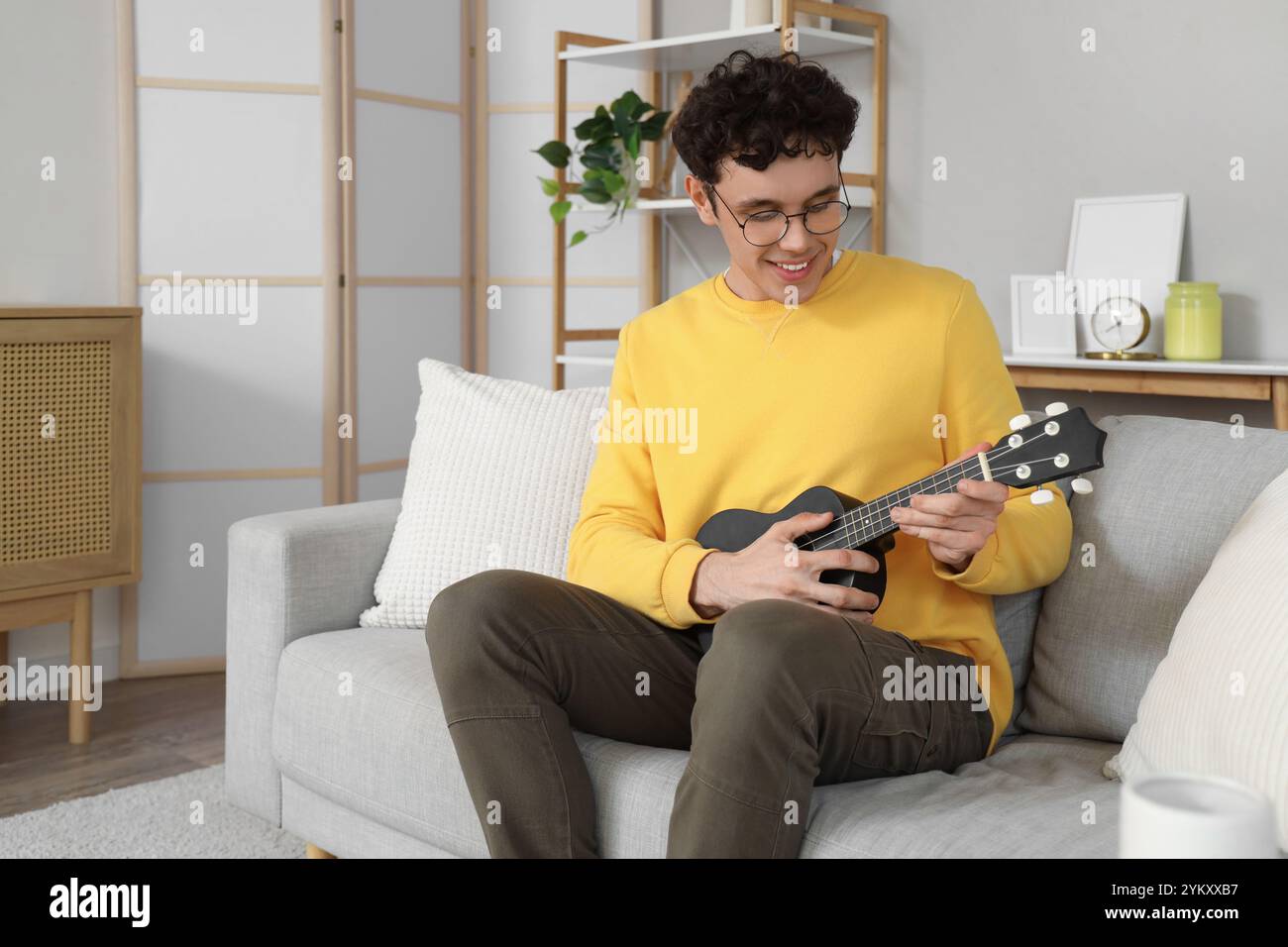 Young smiling man playing ukulele hi-res stock photography and images ...