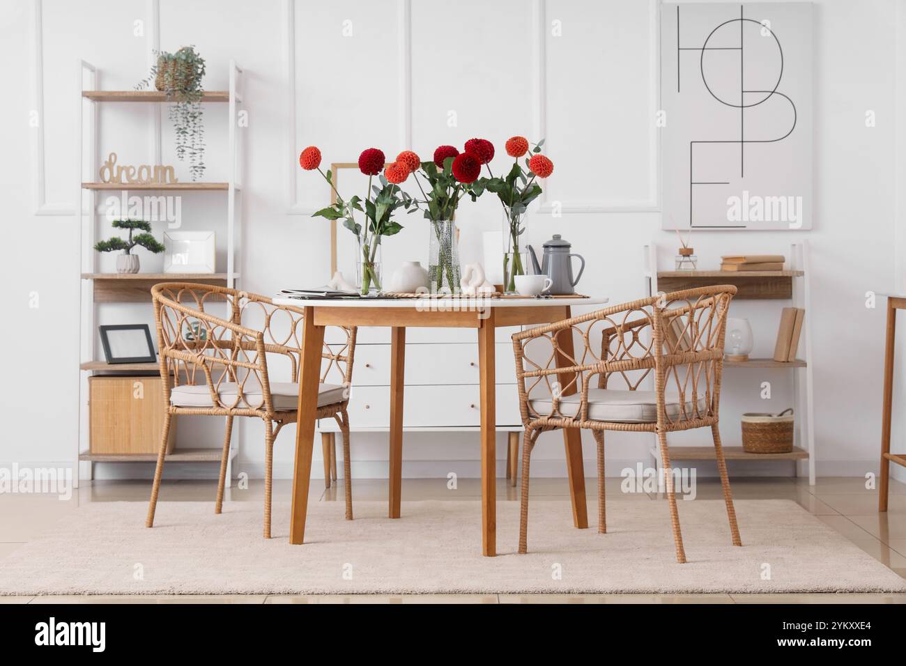Vases with beautiful dahlia flowers and tea set on dining table at home ...