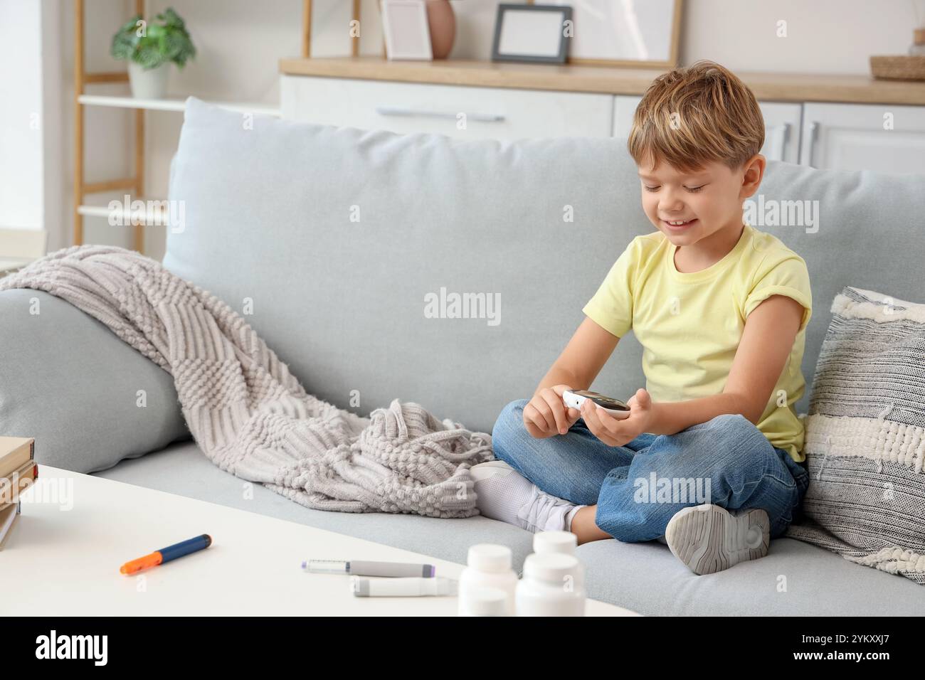 Little diabetic boy using glucometer on sofa at home Stock Photo - Alamy