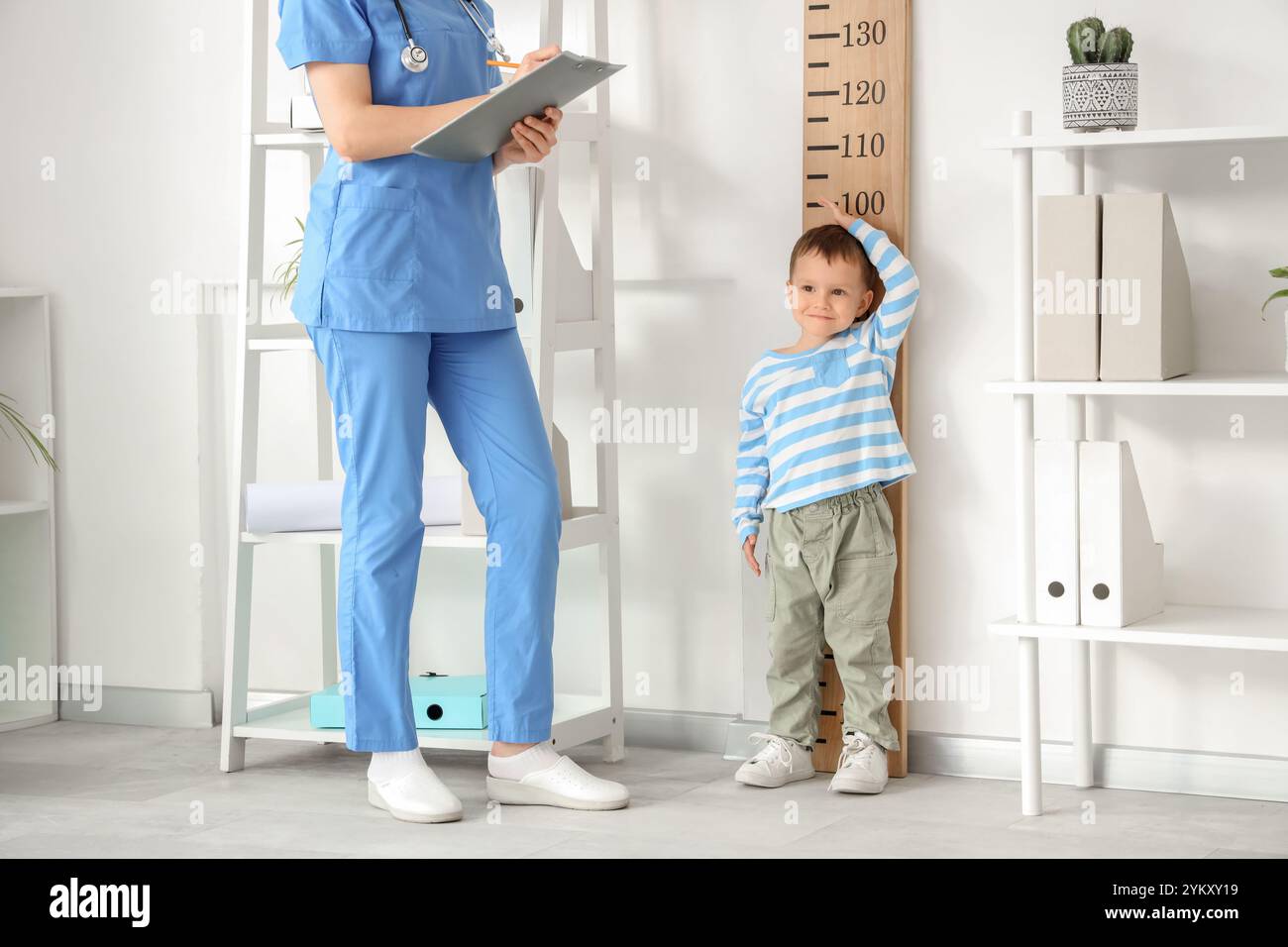 Female pediatrician with cute little boy measuring height near ...