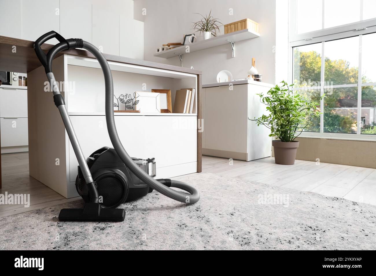 Modern vacuum cleaner near table in kitchen interior Stock Photo - Alamy