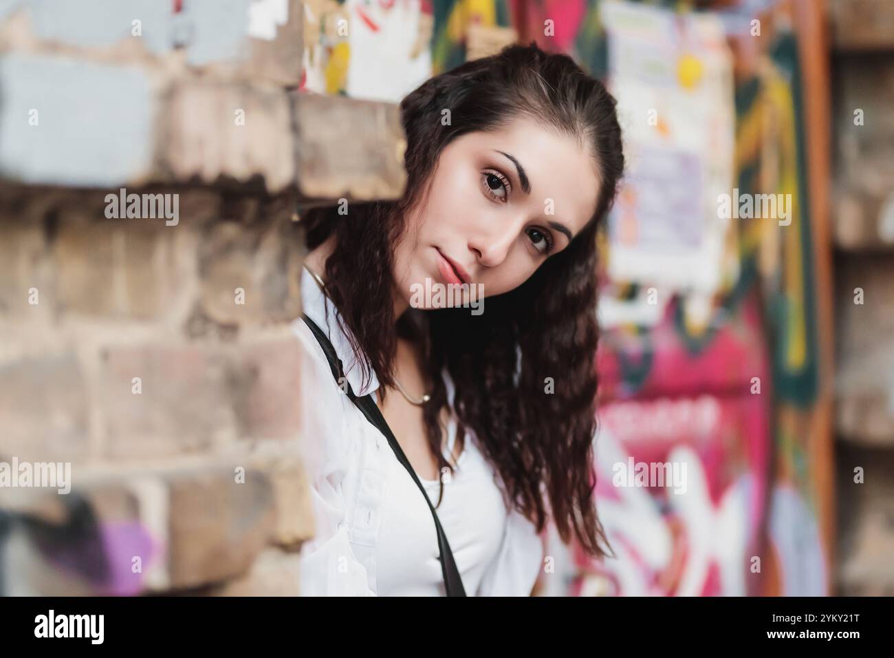 Young woman poses playfully in urban art environment with colorful ...