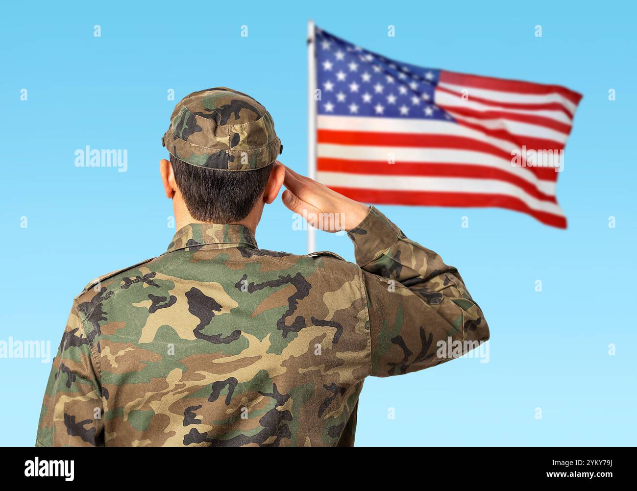 Rear view of a young soldier standing to a the US flag and saluting ...