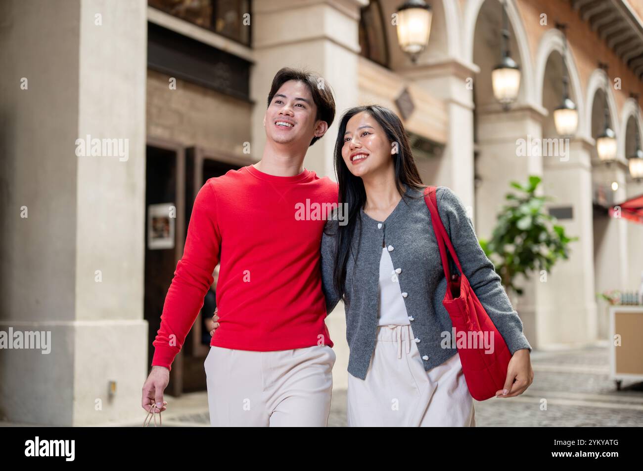 A charming, happy young Asian couple in cozy clothes are enjoying ...