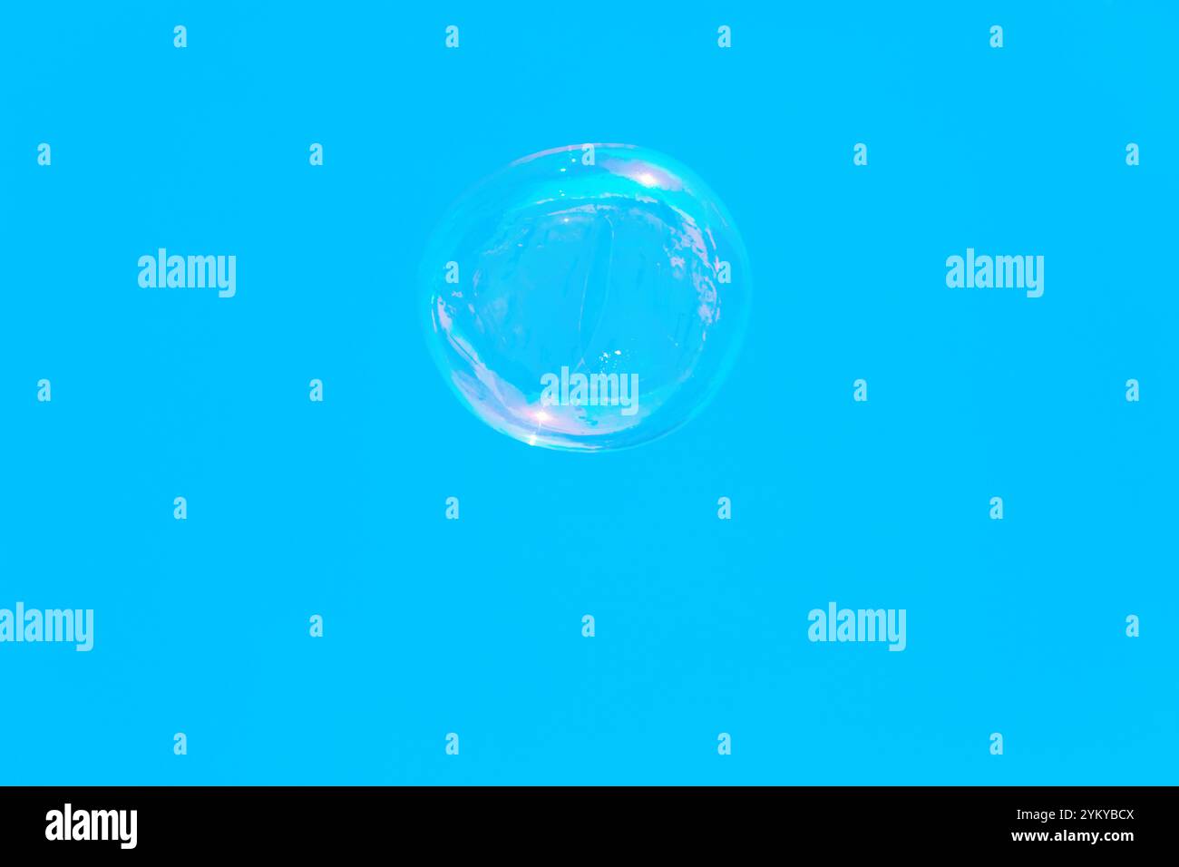 Single transparent bubble floating against a bright blue background ...
