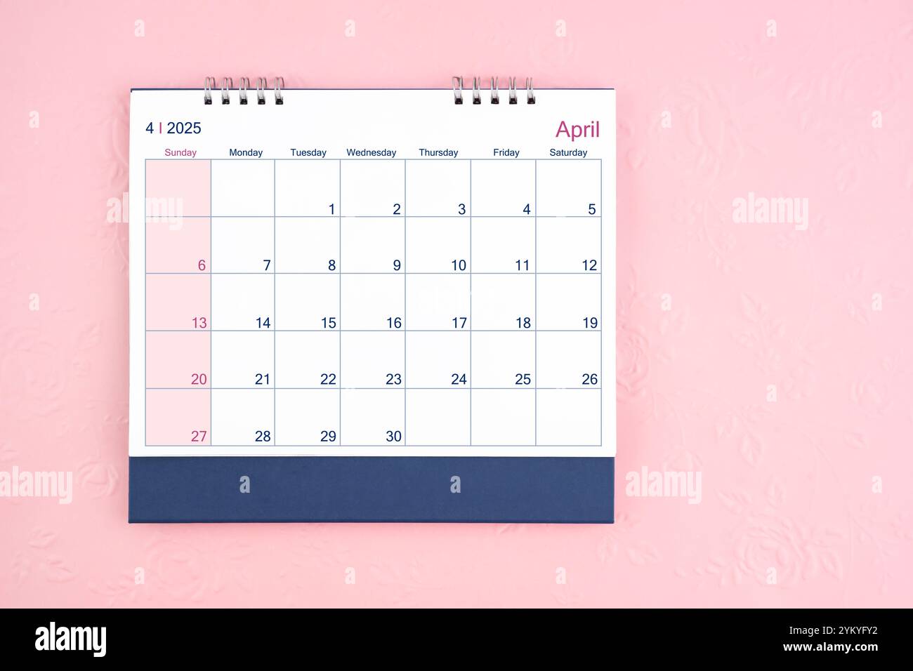 Directly above view of April 2025 desk calendar on pink background with ...