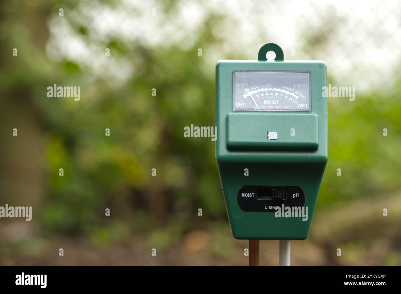 A detailed view of a green soil moisture and pH meter used in a garden ...