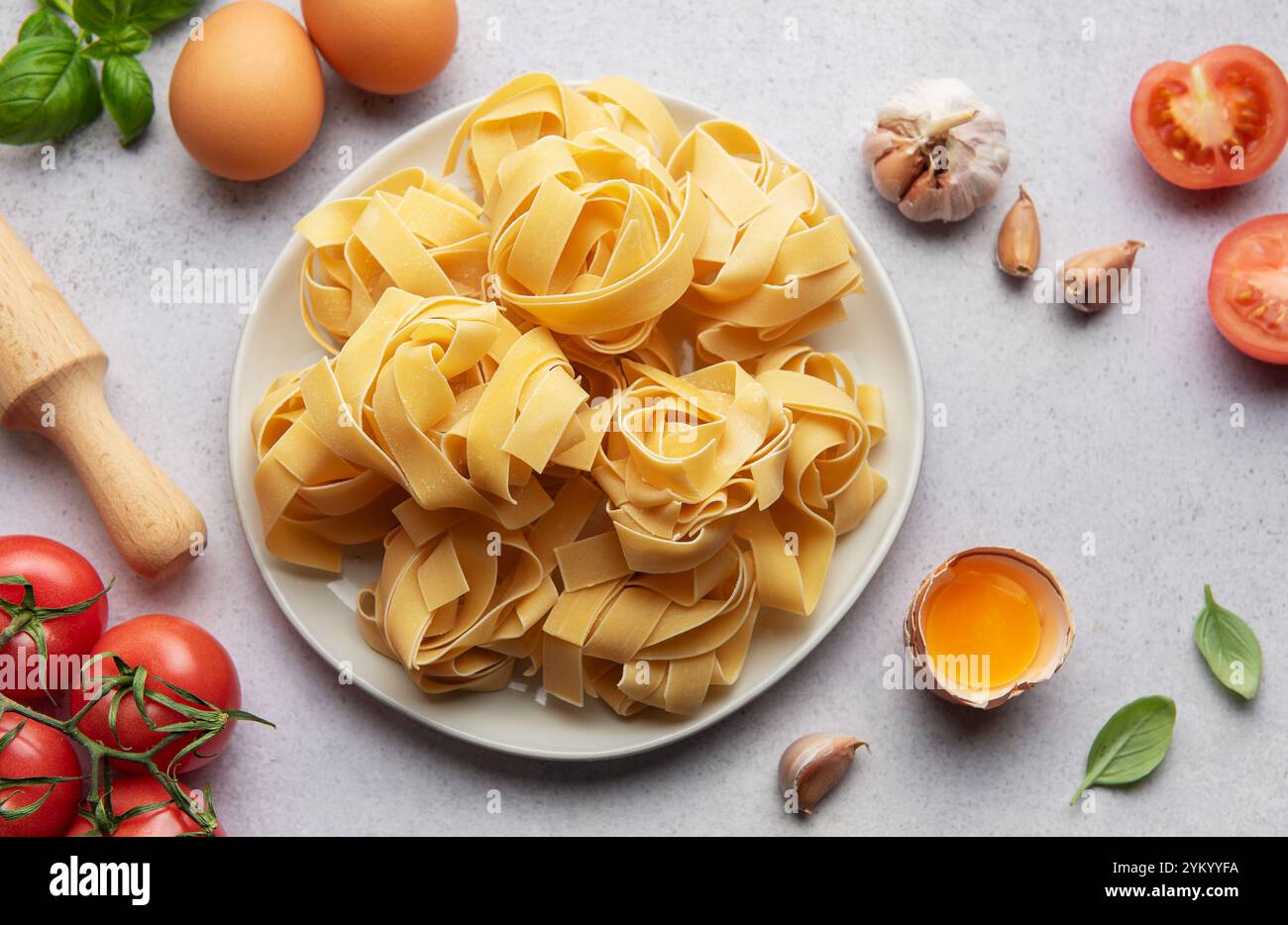 Plate of raw, uncooked pappardelle pasta surrounded by fresh ...