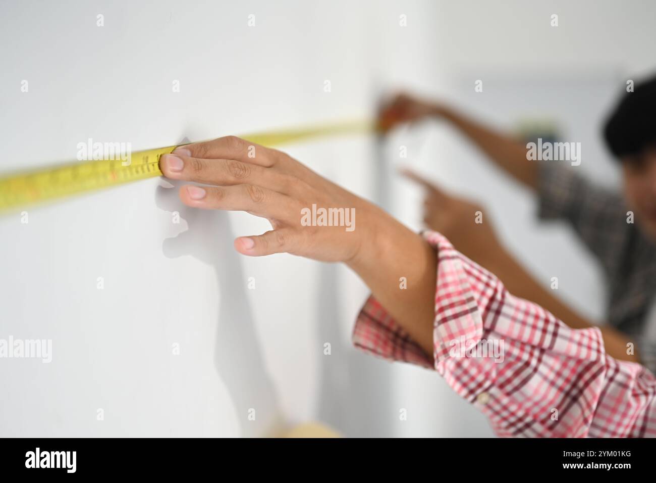 Two people measuring a wall with tape measure for home renovation ...