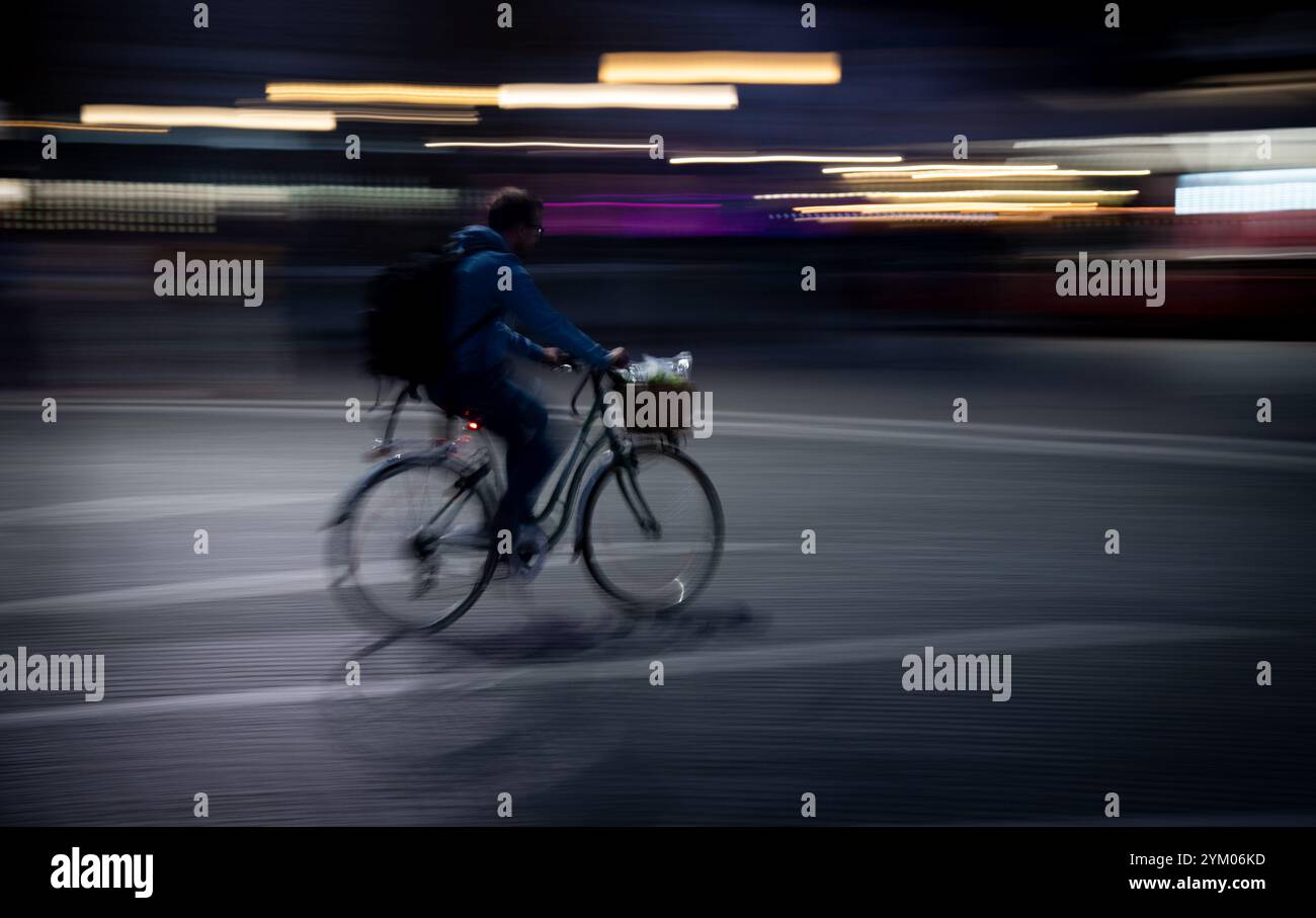 Unrecognized person cycling in the city at night. Blurred lights sense ...