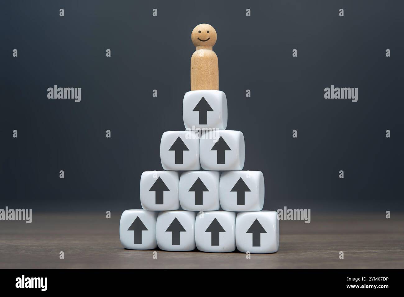 A wooden figure with a smiley face stands atop a pyramid of white cubes ...