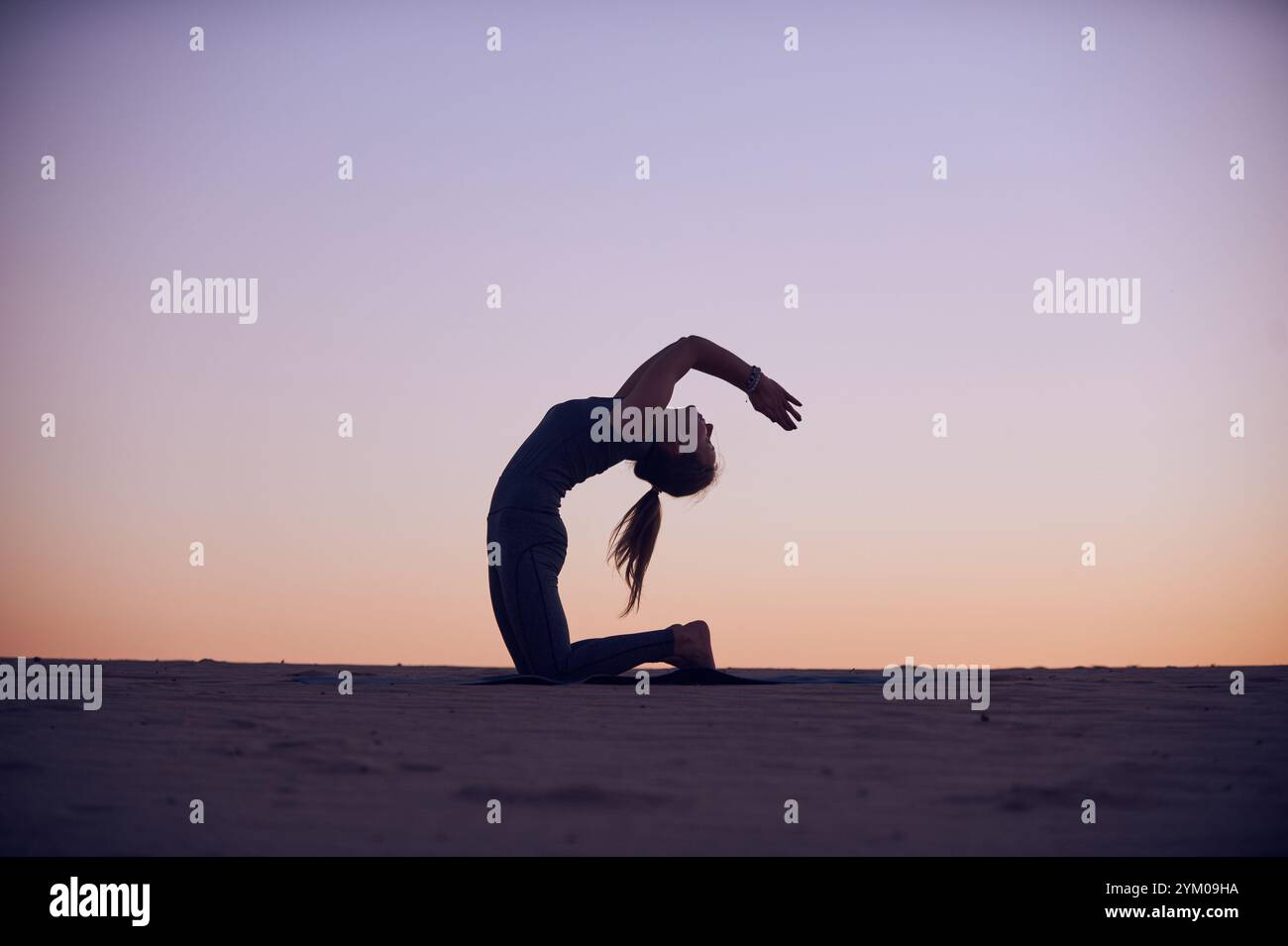 Evening yoga practice in a serene desert landscape with a woman ...