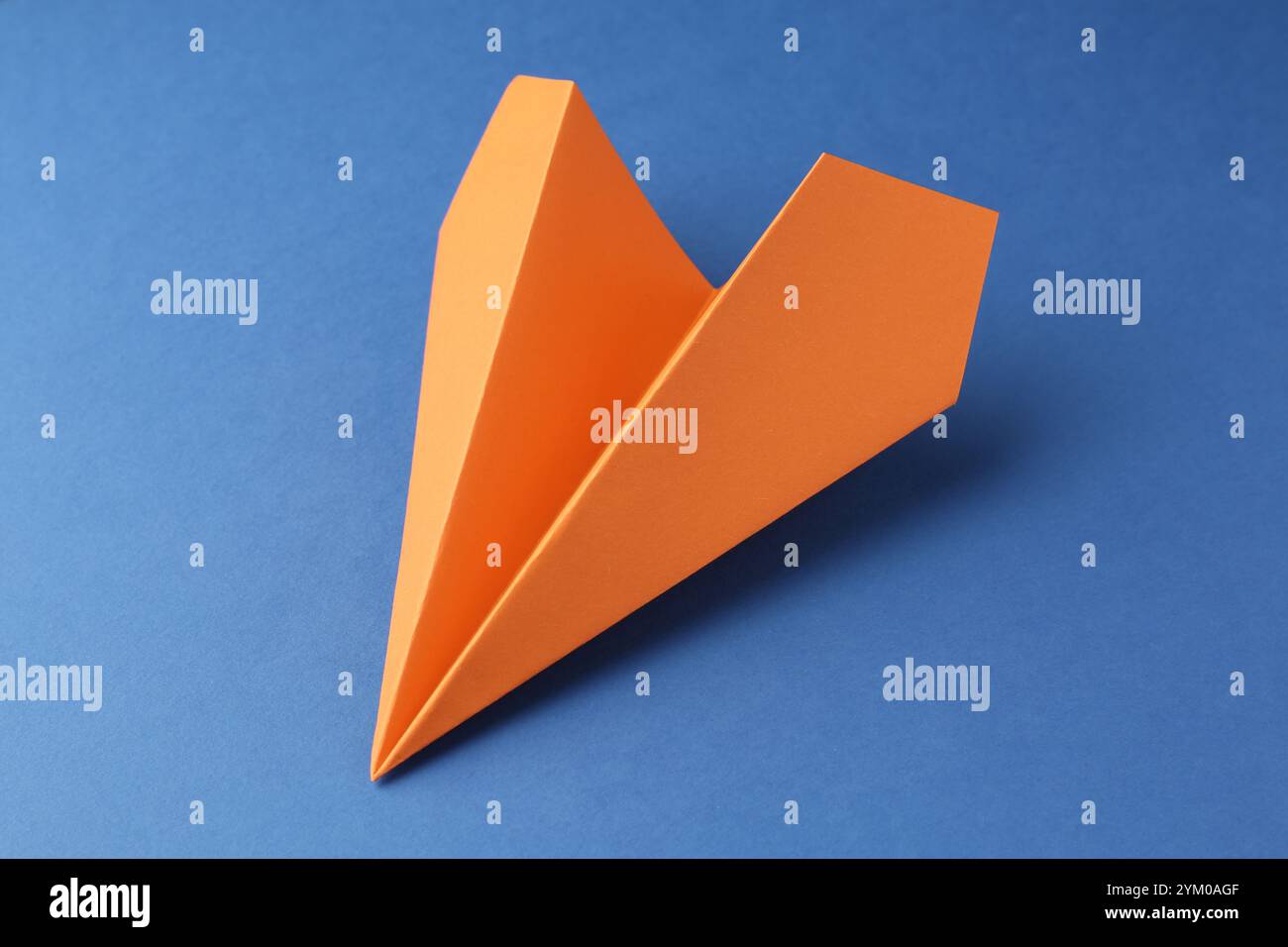 One handmade orange paper plane on blue background Stock Photo - Alamy