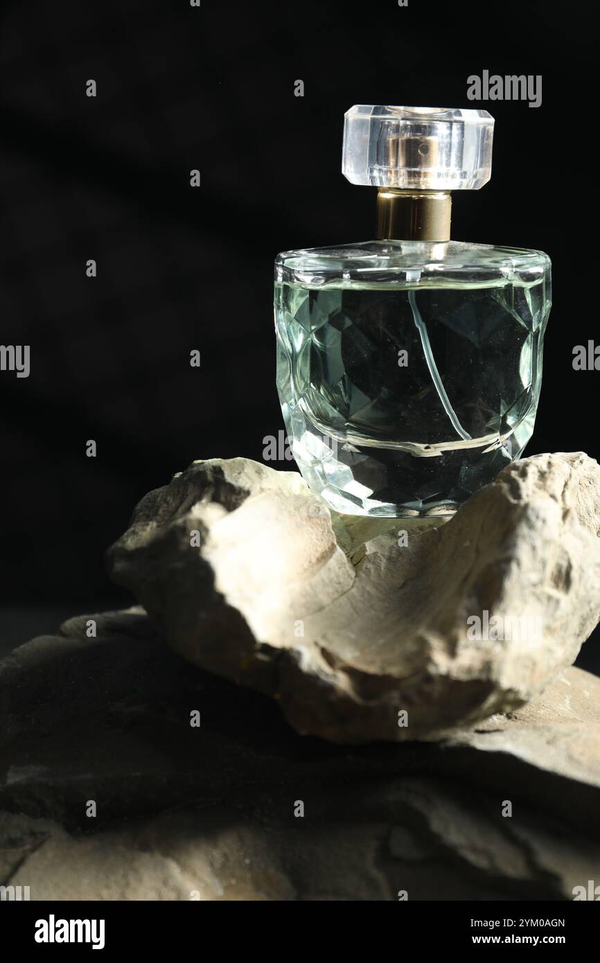 Bottle of fragrant perfume on rock against dark background Stock Photo ...