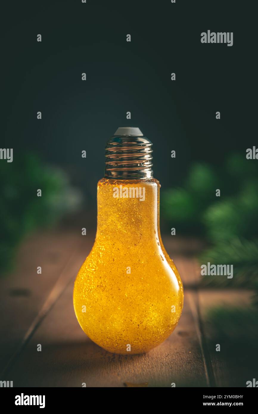 A light bulb with a golden liquid surrounded by fir branches, Christmas ...