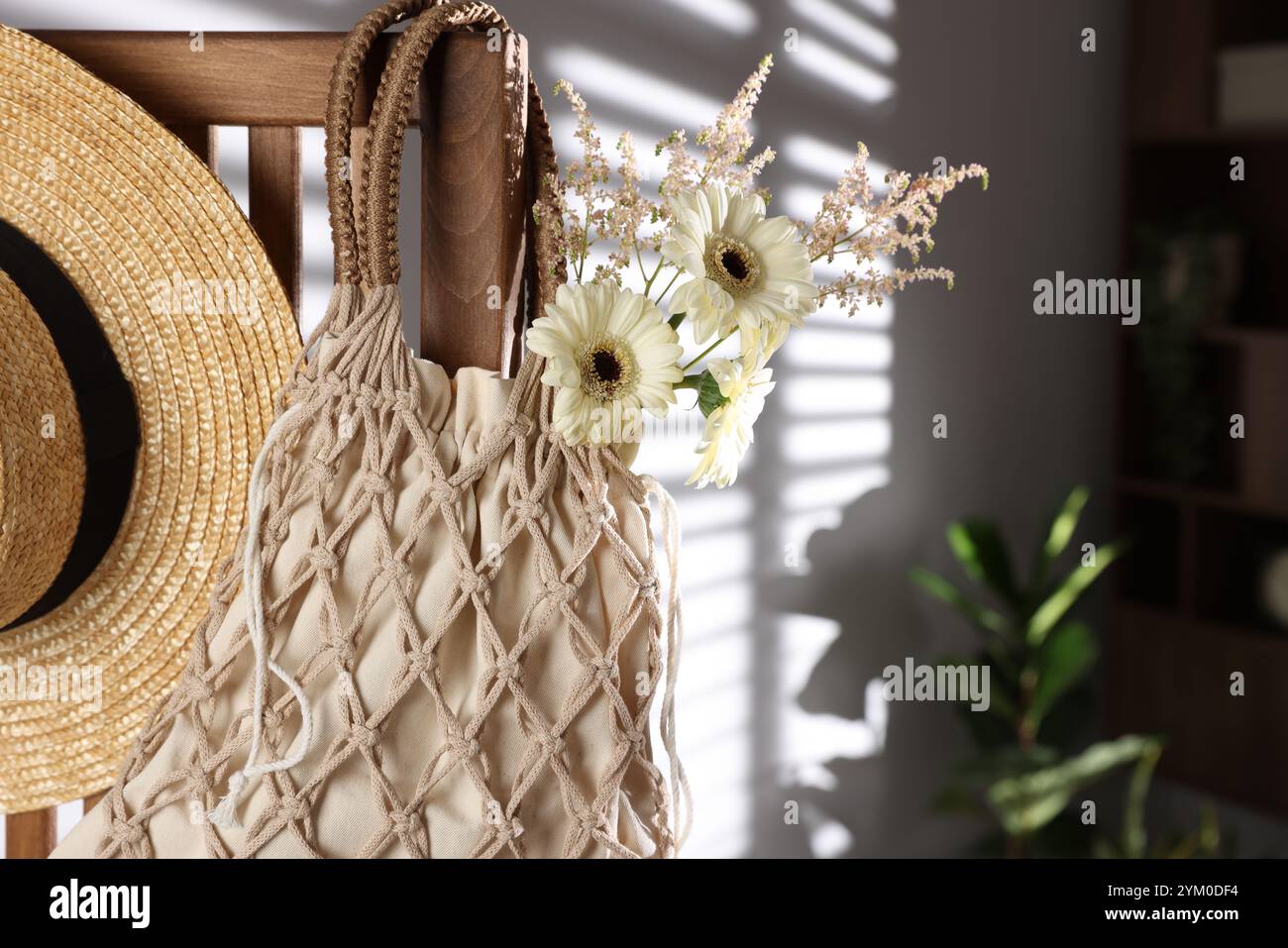 Handmade macrame shopping bag with flowers and straw hat on wooden ...