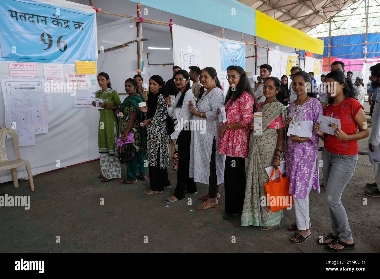 Indian women wait in a queue to cast their vote during Maharashtra ...