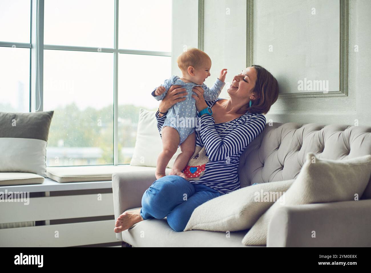 Mother and baby enjoying playful moments in a cozy, sunlit living room ...