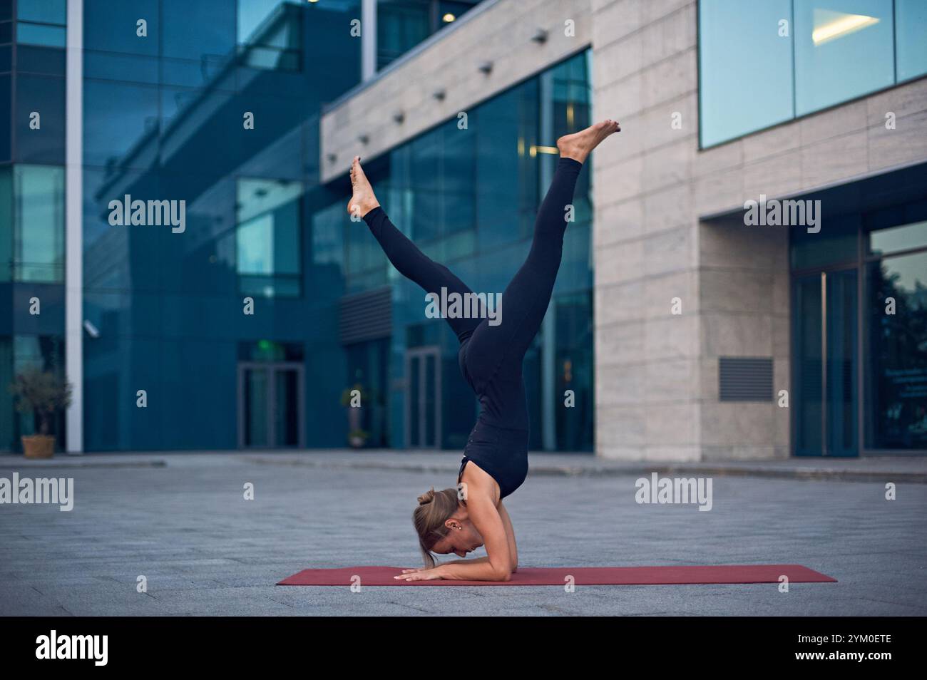 Yoga practitioner performs advanced pose outdoors in urban setting ...