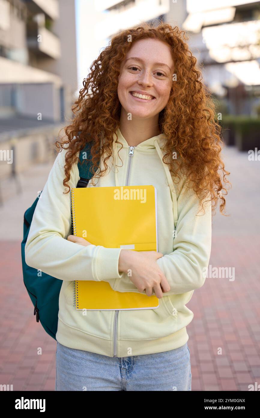 Smiling student holding notebook and wearing backpack on campus Stock ...