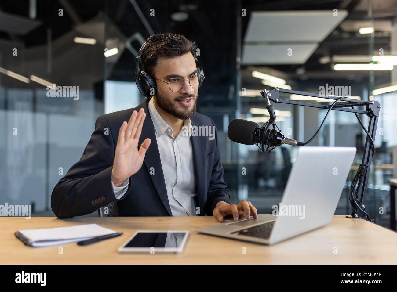 Man in office records podcast using microphone and laptop, wearing ...