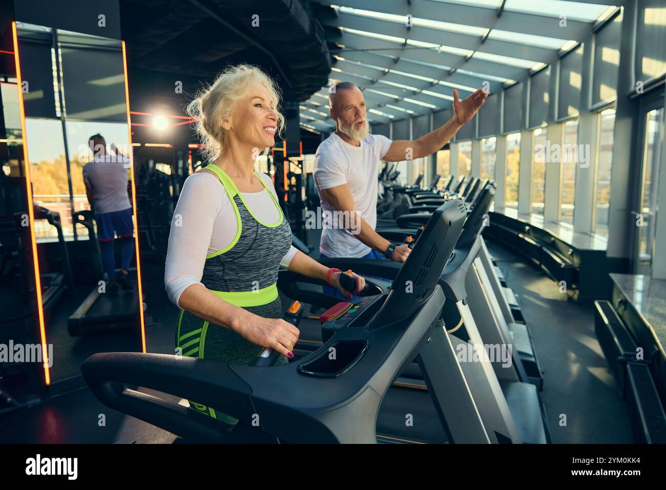 Elderly man and woman, couple engaging in treadmill workout in vibrant ...