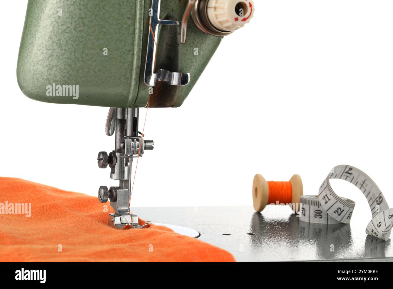 Sewing machine with orange fabric, measuring tape and spool of thread ...
