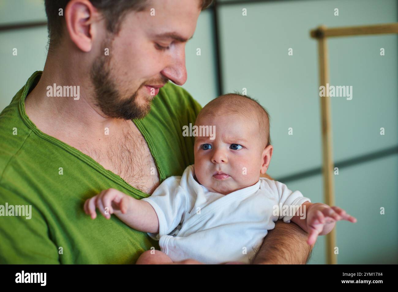 Father cradles his newborn baby, sharing a tender moment indoors in a ...