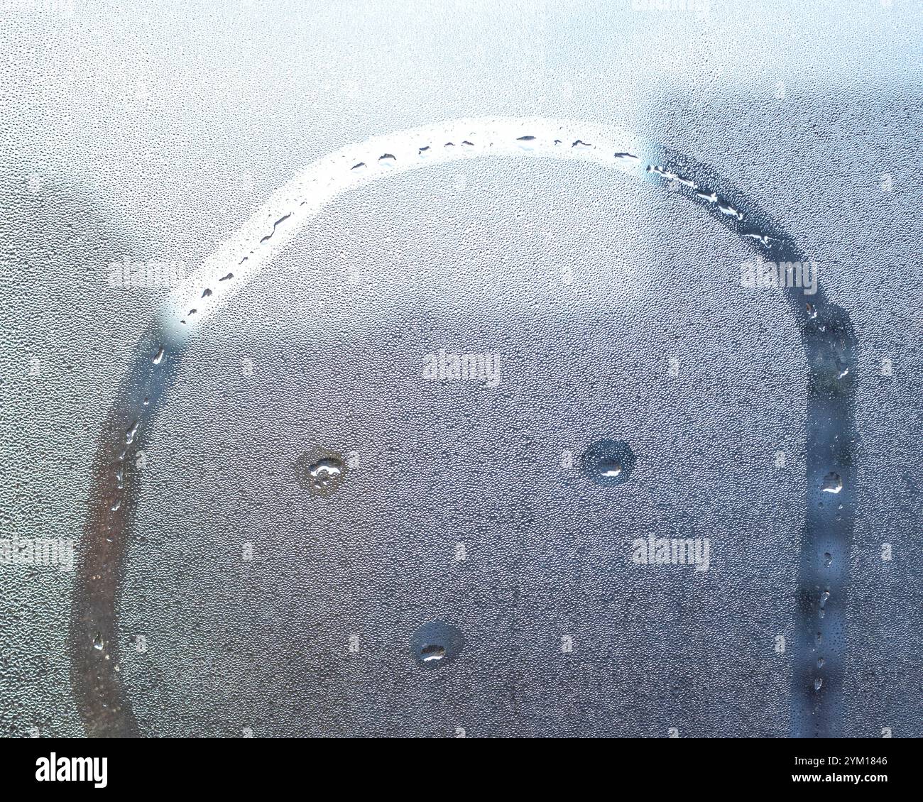 Face drawn in condensation on the inside of a glass window pane on a ...