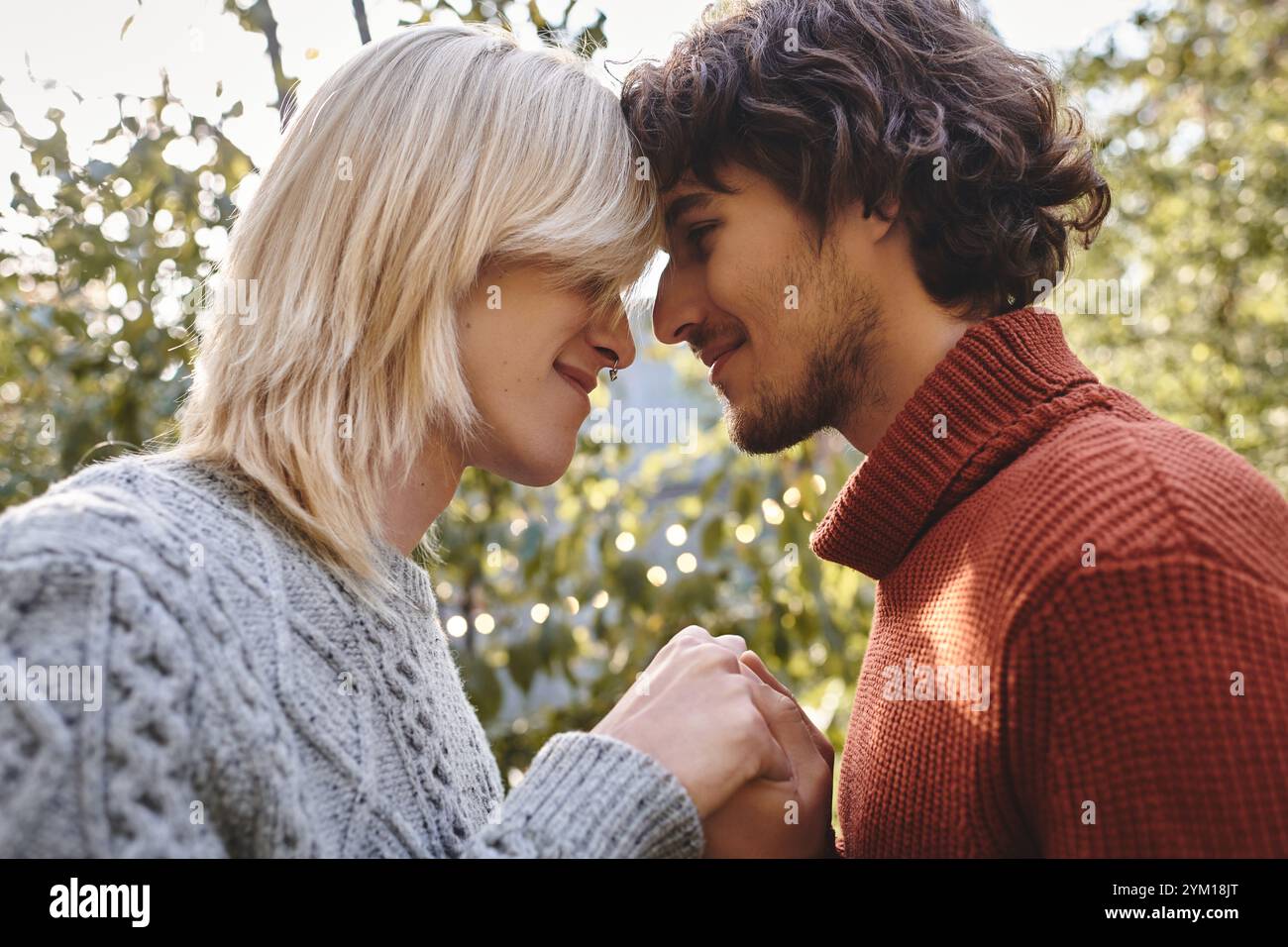 Two handsome young people stand close, their foreheads gently touching ...