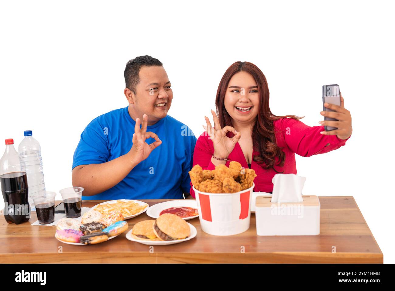 A happy couple is enjoying delicious fast food while taking fun selfies ...
