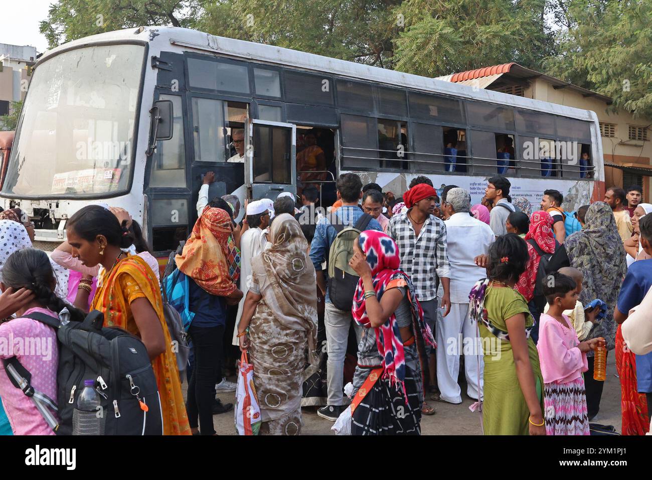 A crowd of passengers wait to board a bus in Shirpur, Maharashtra ...