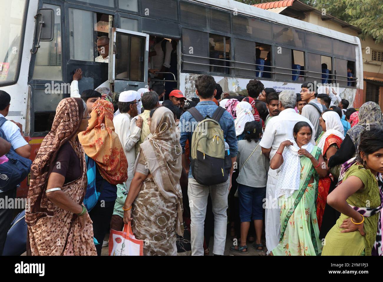 A crowd of passengers wait to board a bus in Shirpur, Maharashtra ...