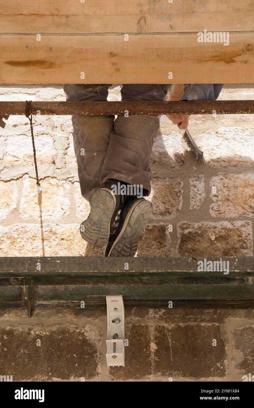 Builder / worker repointing / pointing / mortar, historic stone wall ...