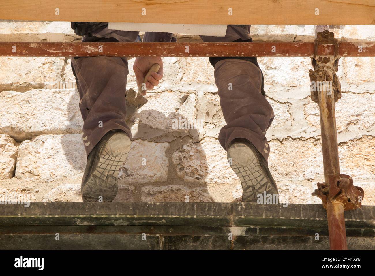 Builder / worker repointing / pointing / mortar, historic stone wall ...