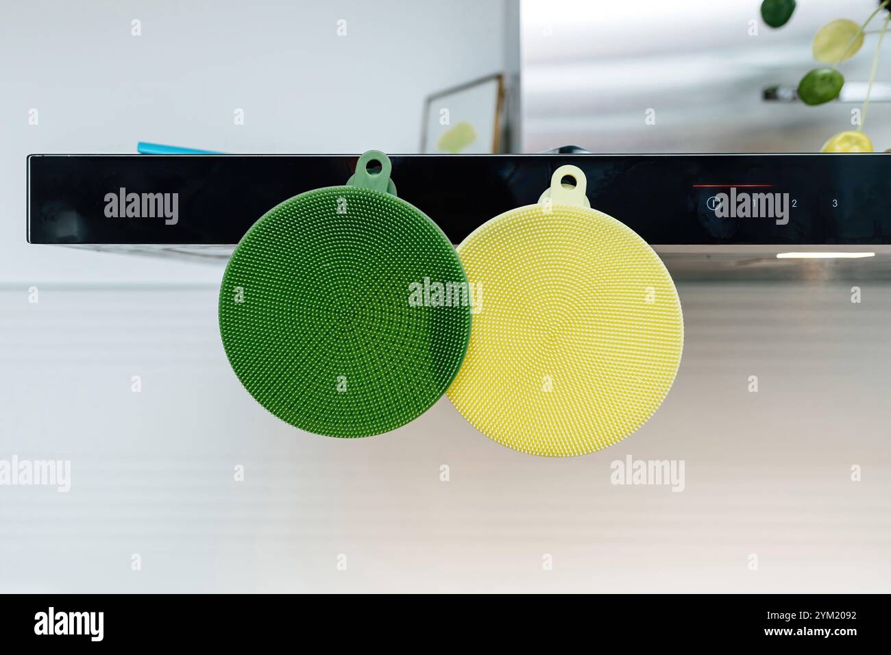 Two colorful silicone scrubbers, one green and one yellow, hanging ...