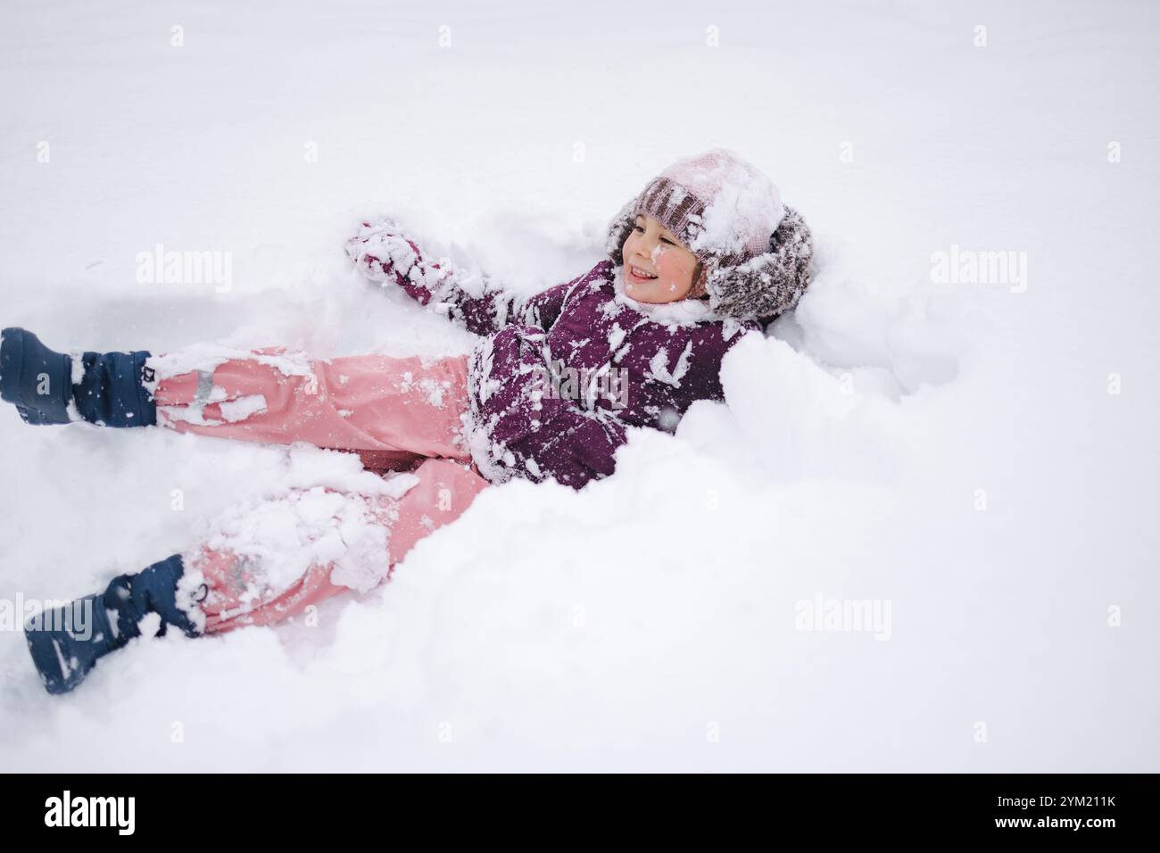 Little girl wearing a cozy winter outfit, happily exploring deep snow ...
