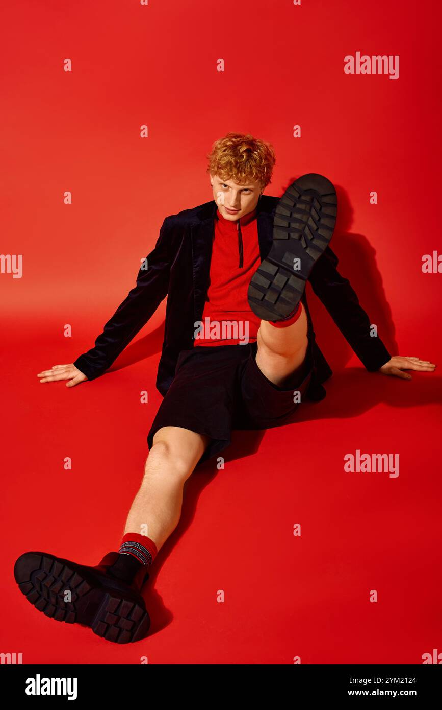 A stylish man showcases his daring holiday outfit against a vibrant red ...