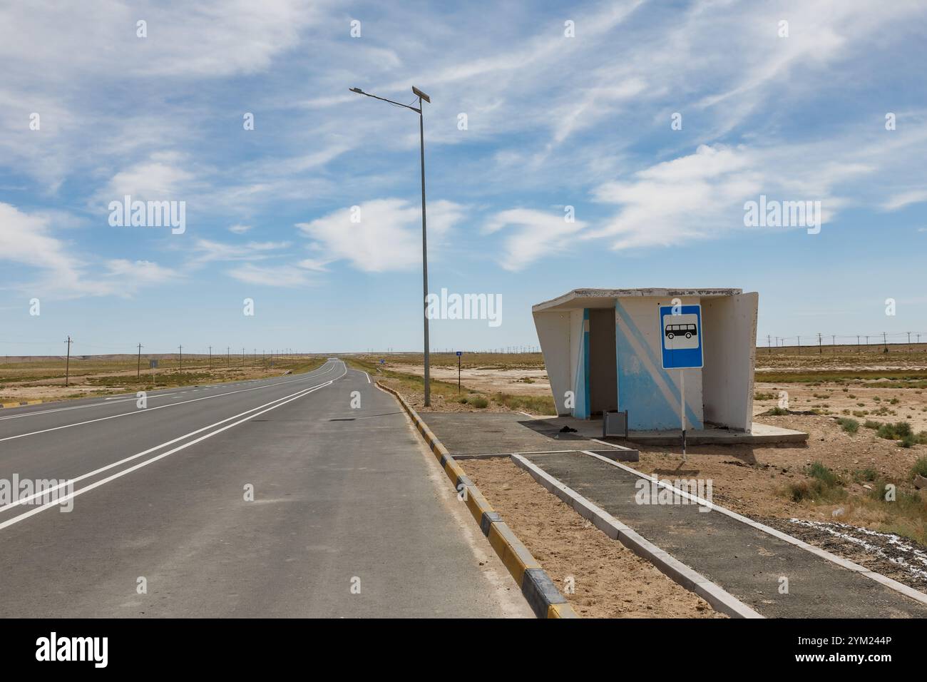 blue bus stop and a bus stop sign on a pillar in the steppe of ...