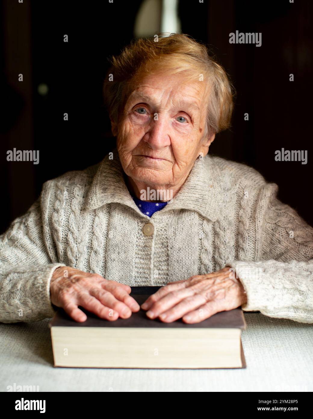 Portrait of an elderly woman stares sternly ahead, her hands resting on ...