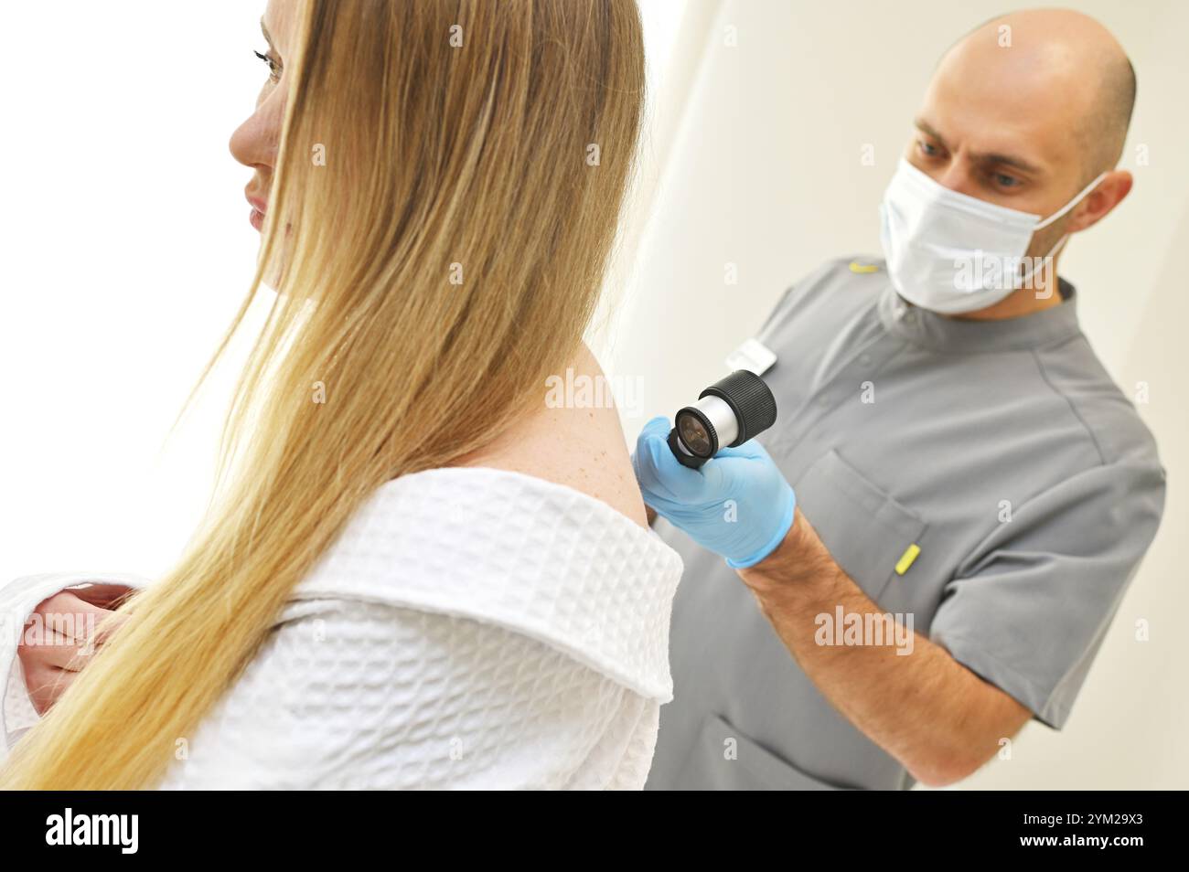 dermatologist examines neoplasms on the patient's skin using a special ...