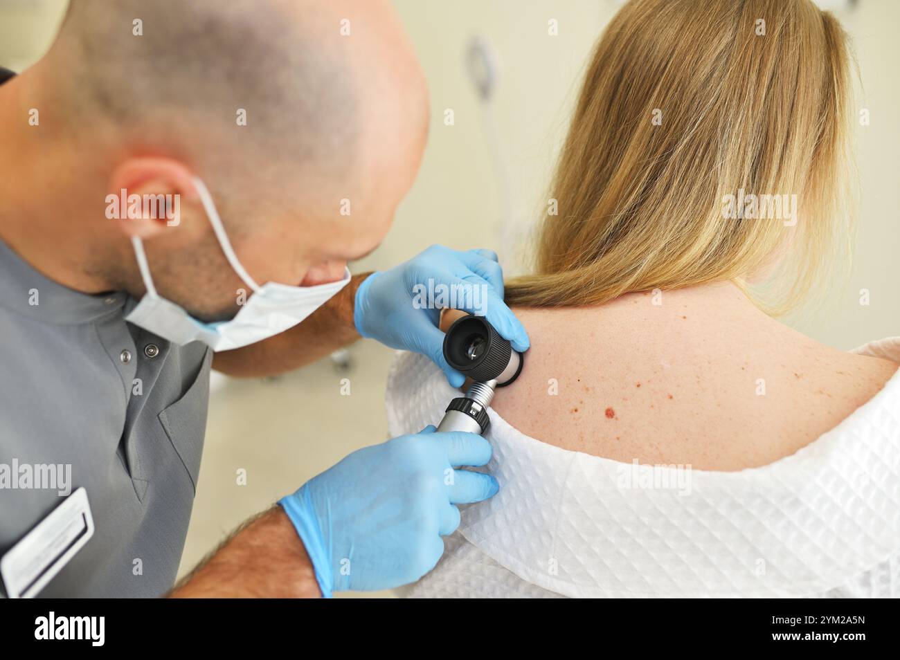 dermatologist examines neoplasms on the patient's skin using a special ...