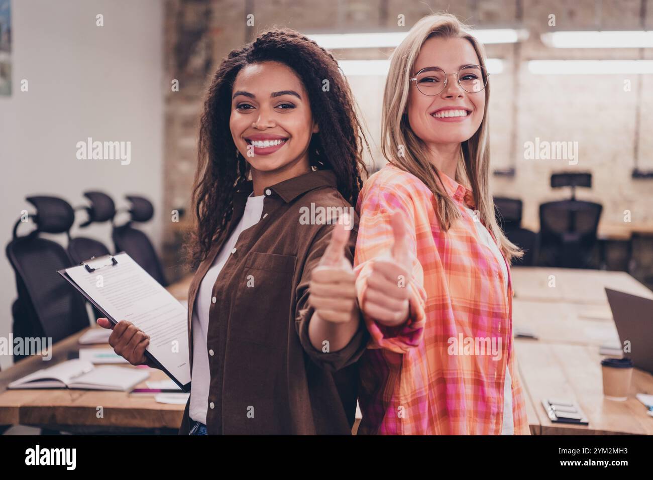 Photo of two corporate workers girls cooperate demonstrate thumb up ...